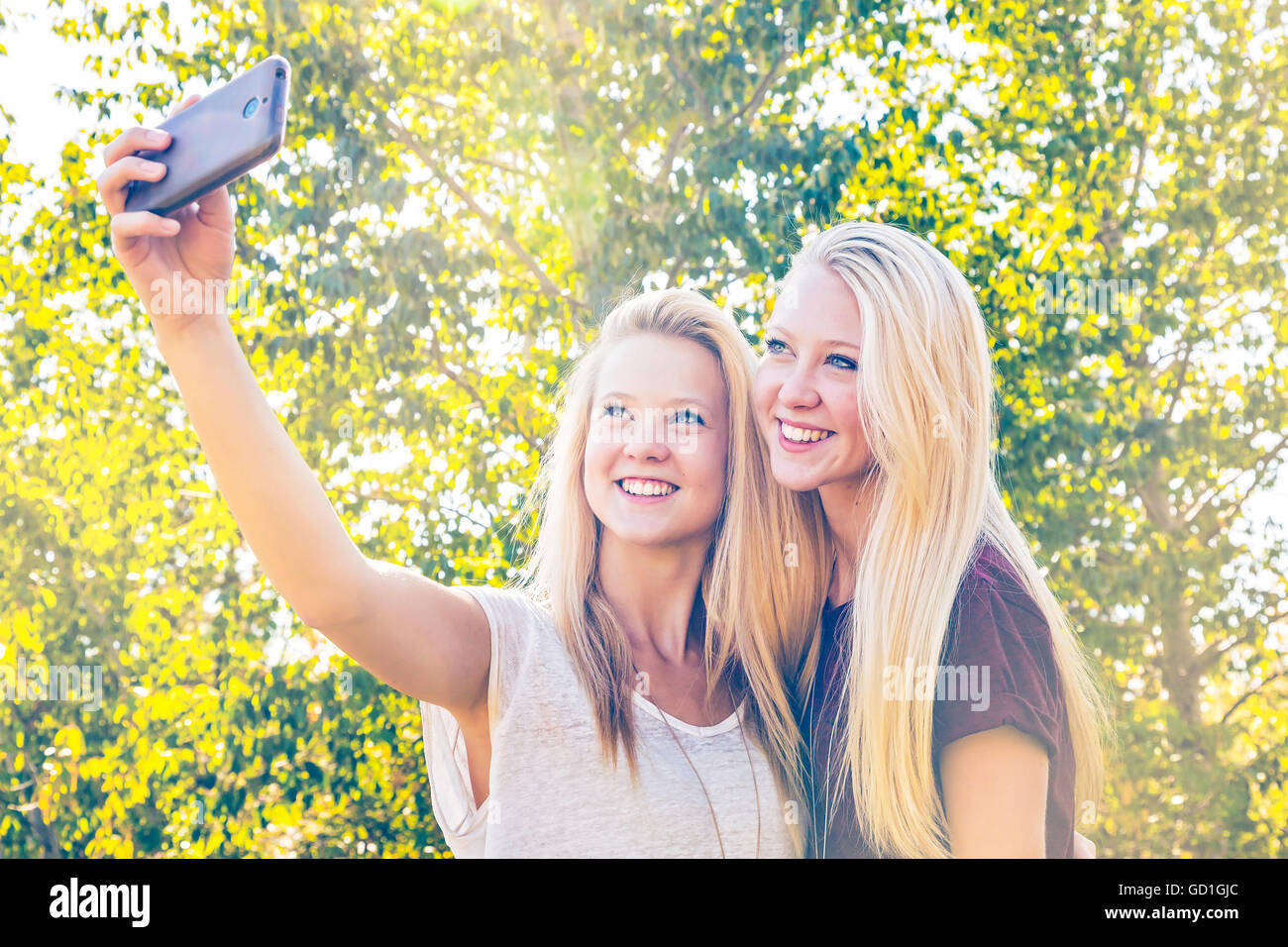 Two Sisters Having Fun Outdoors In A City Park In Autumn And Taking