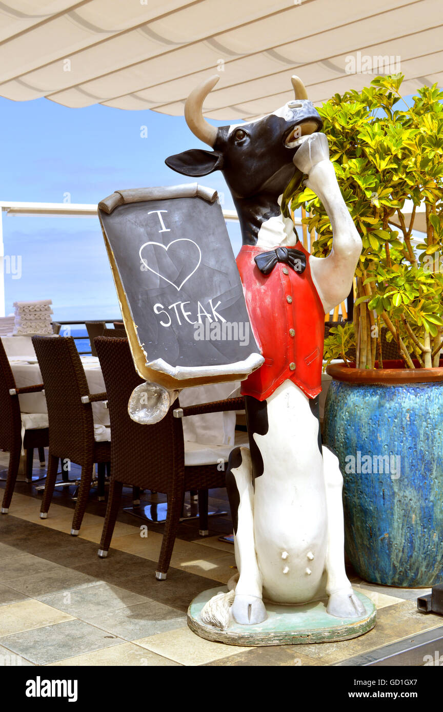 Figurine of a bull holding a restaurant menu I love steak Stock Photo ...