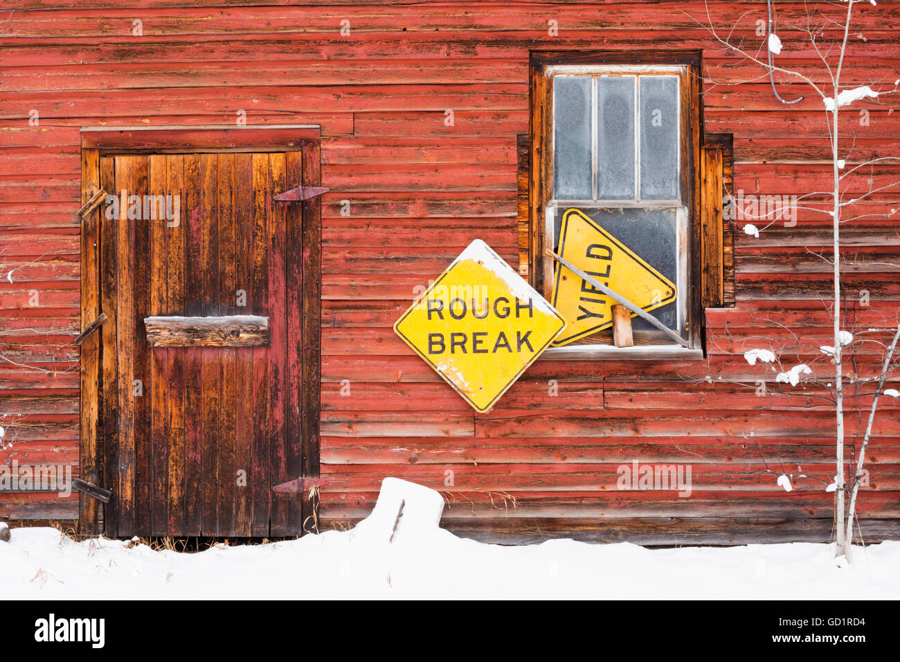 A red wooden building with two yellow signs, saying 'rough break' and ...