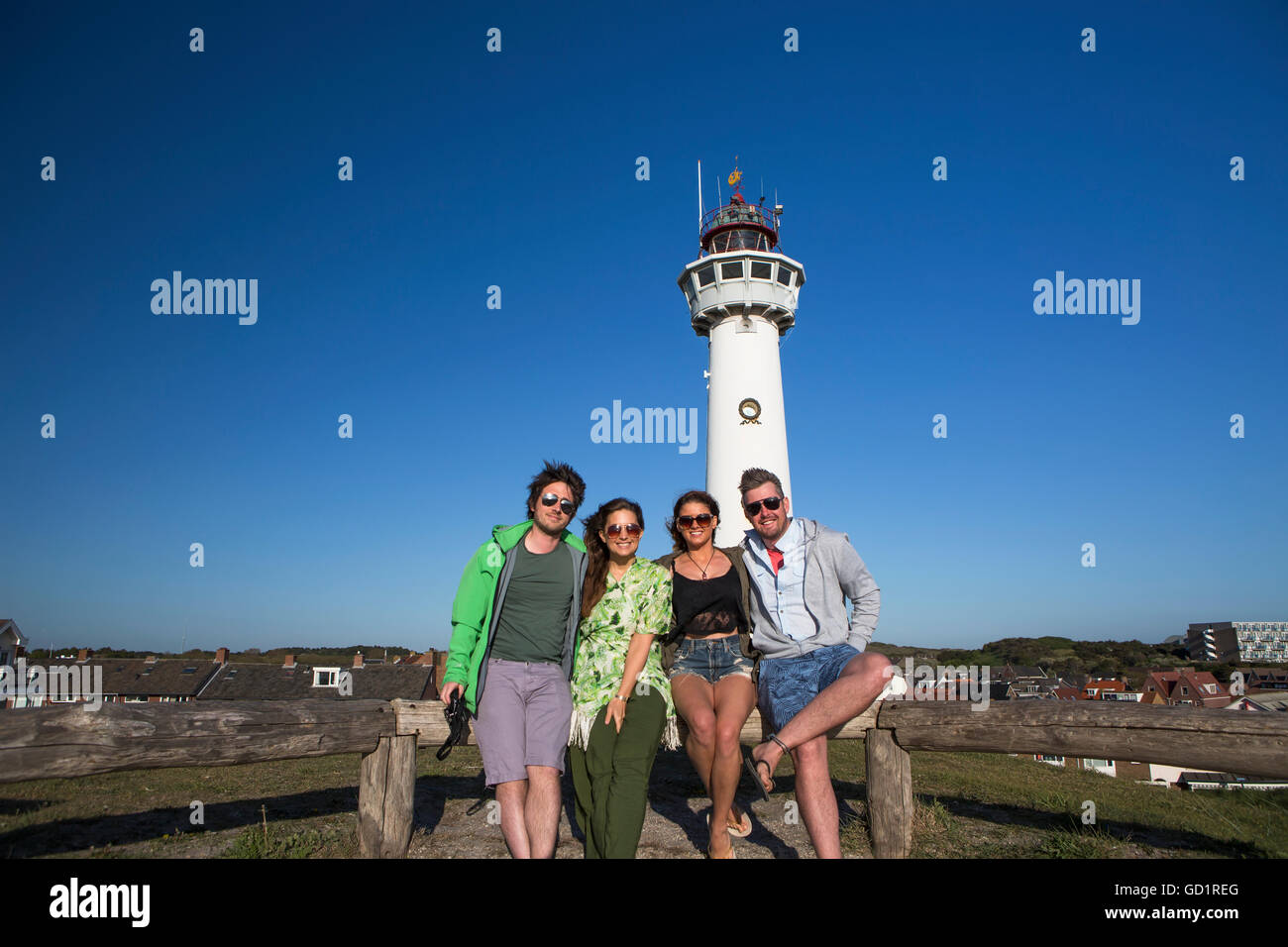 A group of friends standing with a lighthouse in the background outside ...