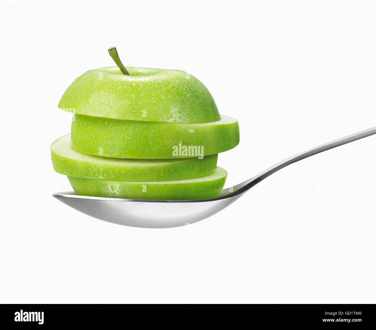 Slices of a cut green apple in a spoon against a white background ...