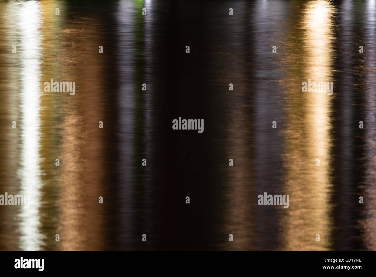 Reflection of yellow and white city lights shimmering on water in ...