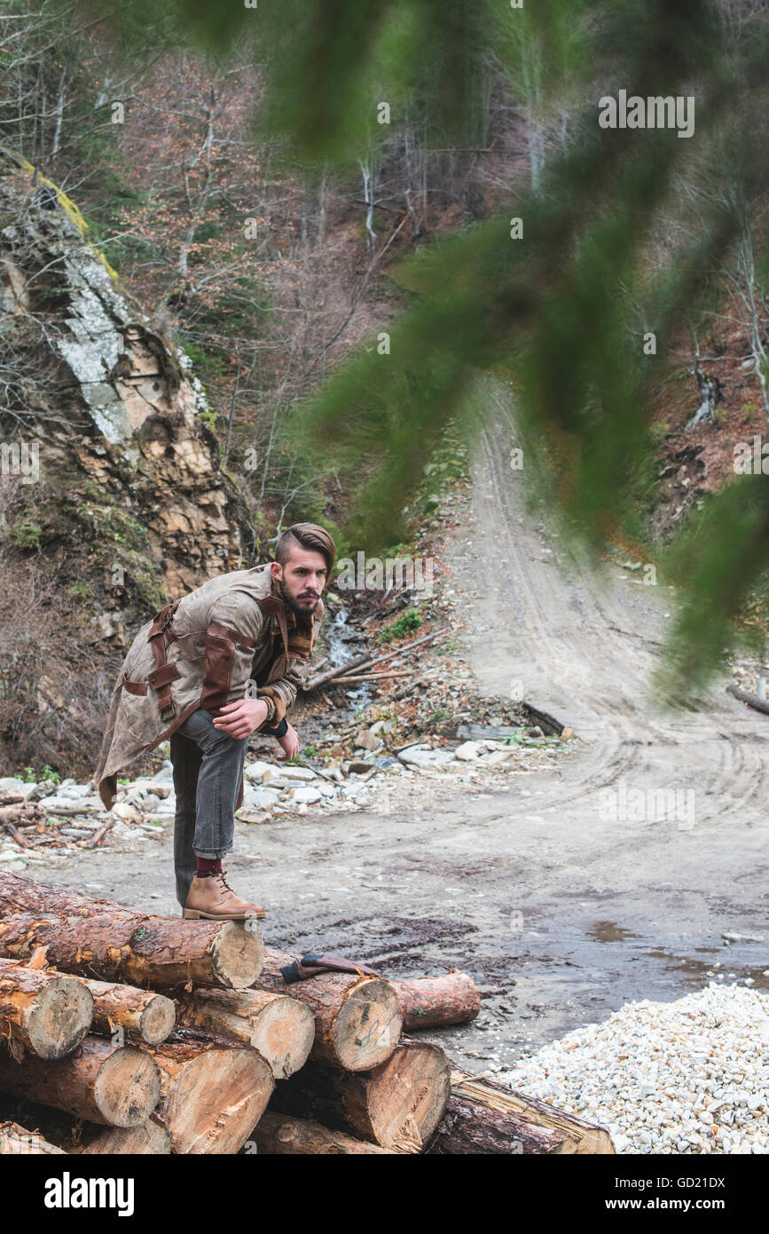 Young men on logs in the forest. Leather and jeans. Outdoor fashion ...