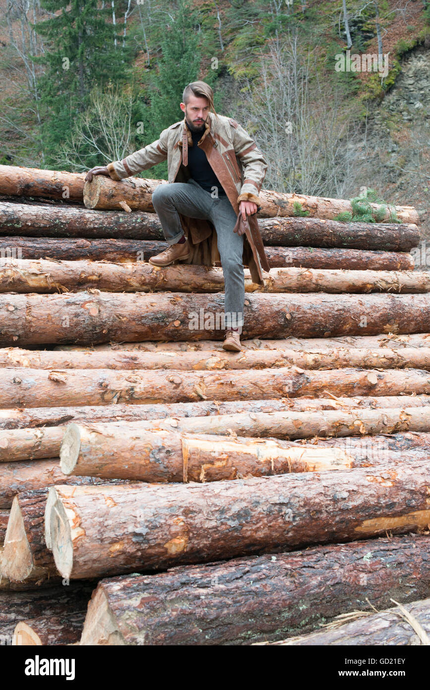 Young men on logs in the forest. Leather and jeans. Outdoor fashion ...