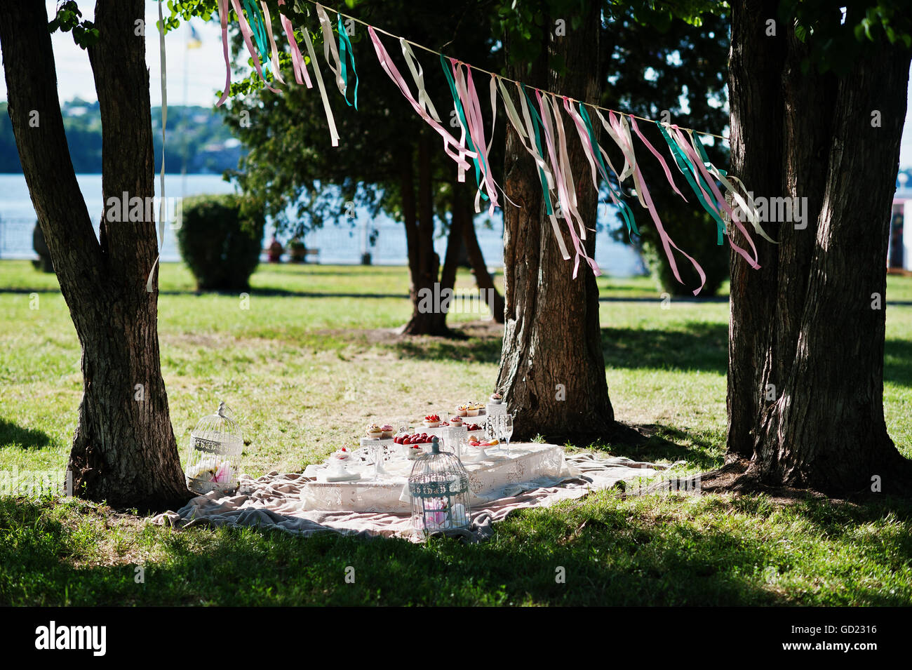 Picnic table with decor and colored ribbons on grass near trees Stock ...