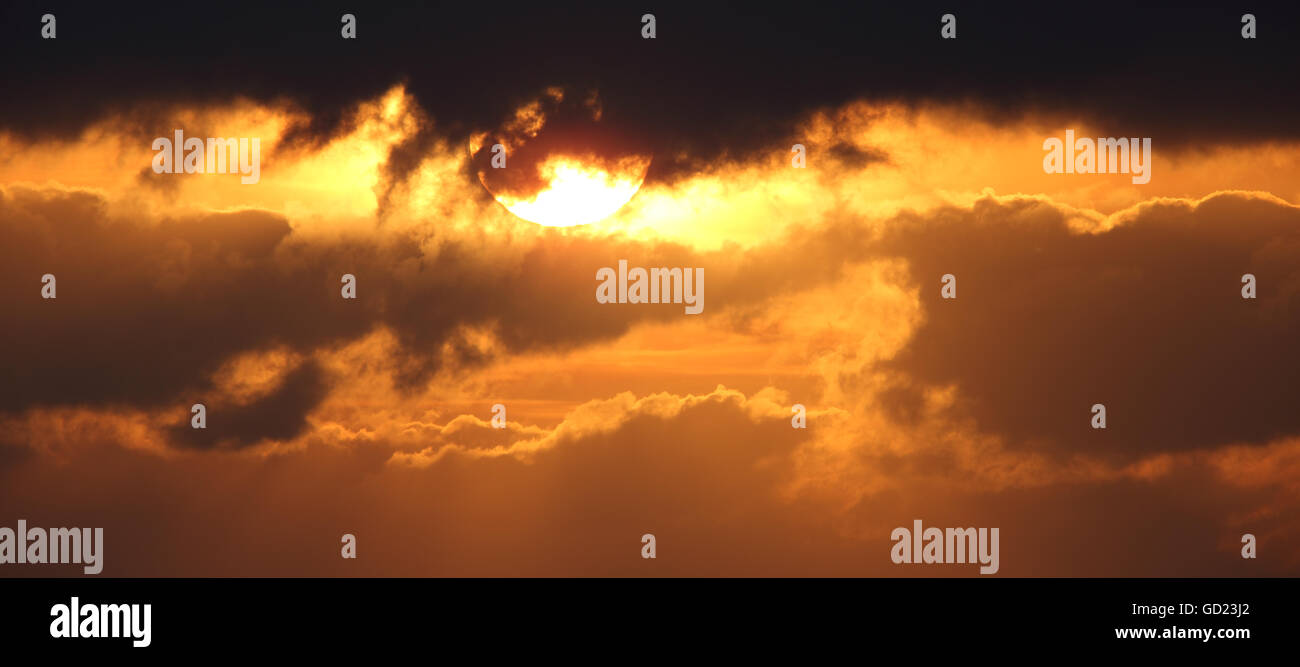 The setting sun with dark clouds Stock Photo - Alamy