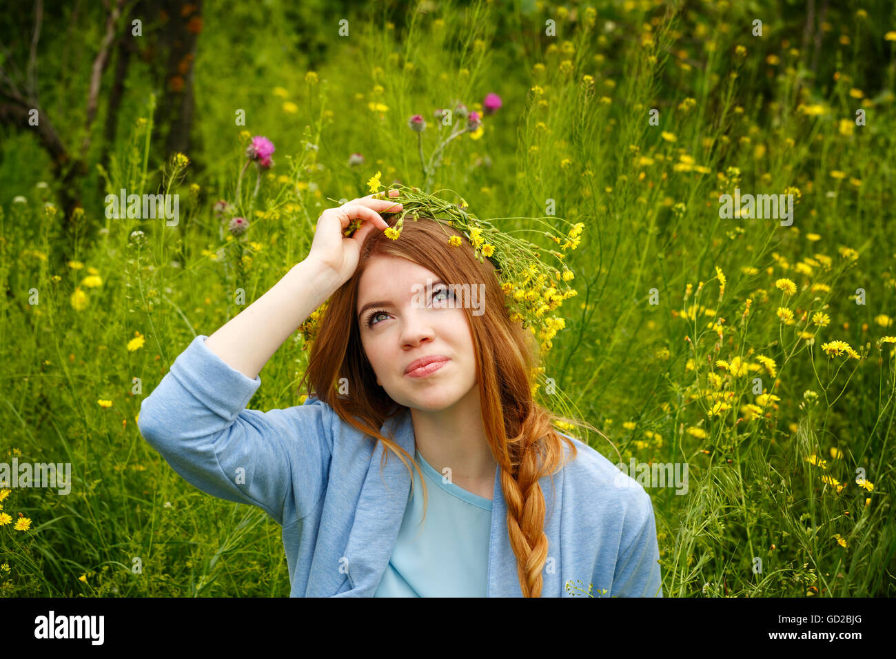 Young attractive girl in a wreath of wild flowers smiling. Hippie girl ...