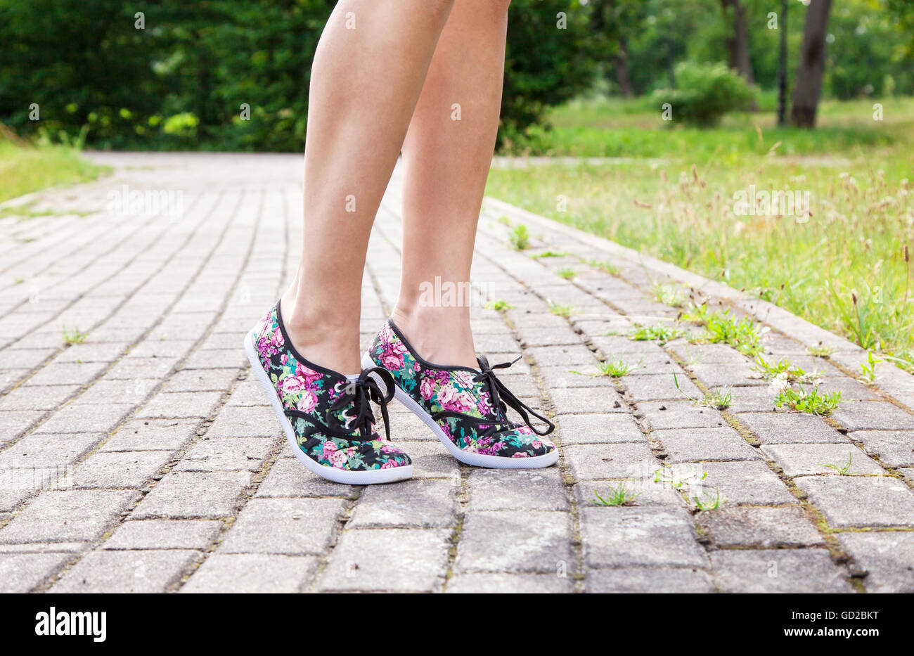 legs of a woman walking on the sidewalk in the park on sunny summer day ...