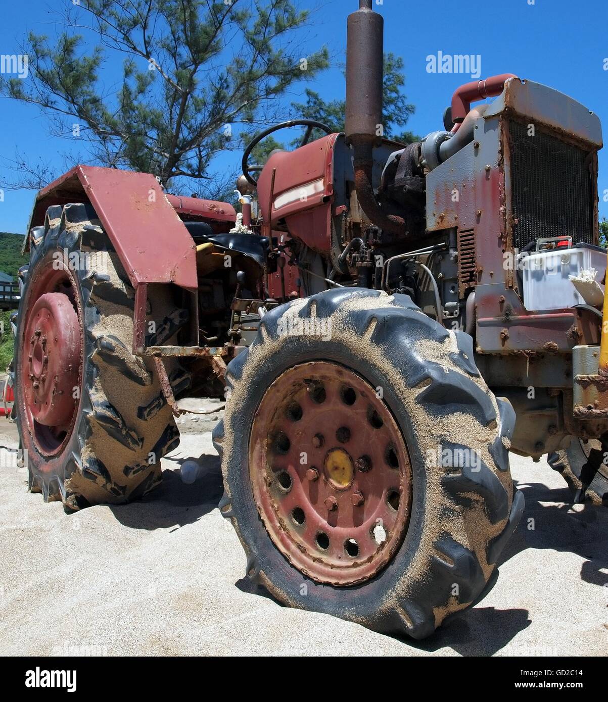 A rusting and corroded old tractor is parked on a sand beach Stock ...
