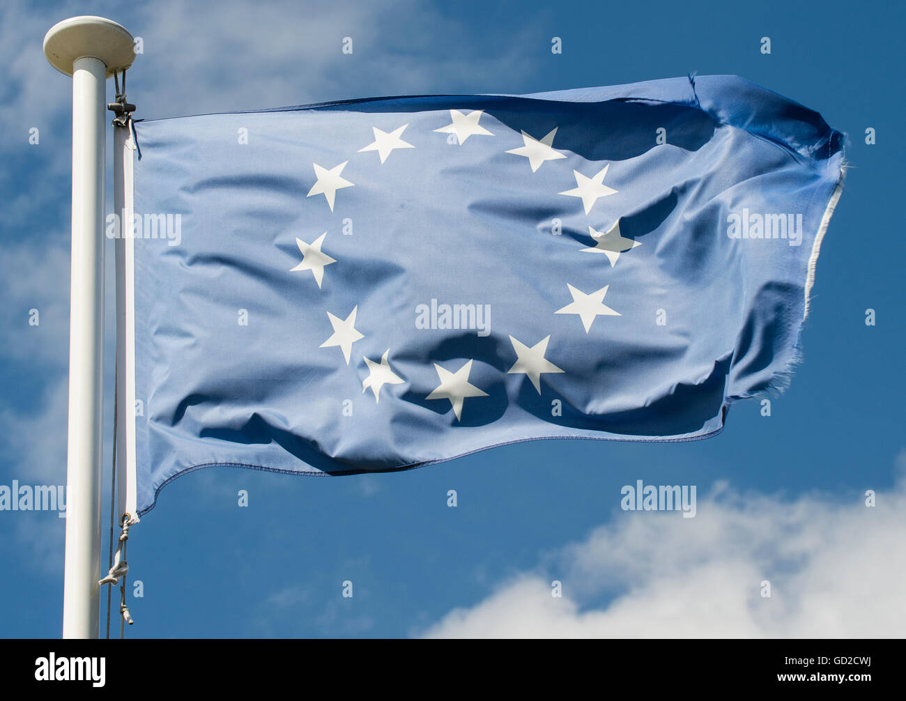 EU flag blowing in wind on white flag pole with blue sky and white ...