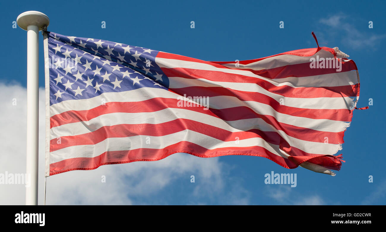 Stars and stripes flag on white flag pole blowing in the wind with blue ...