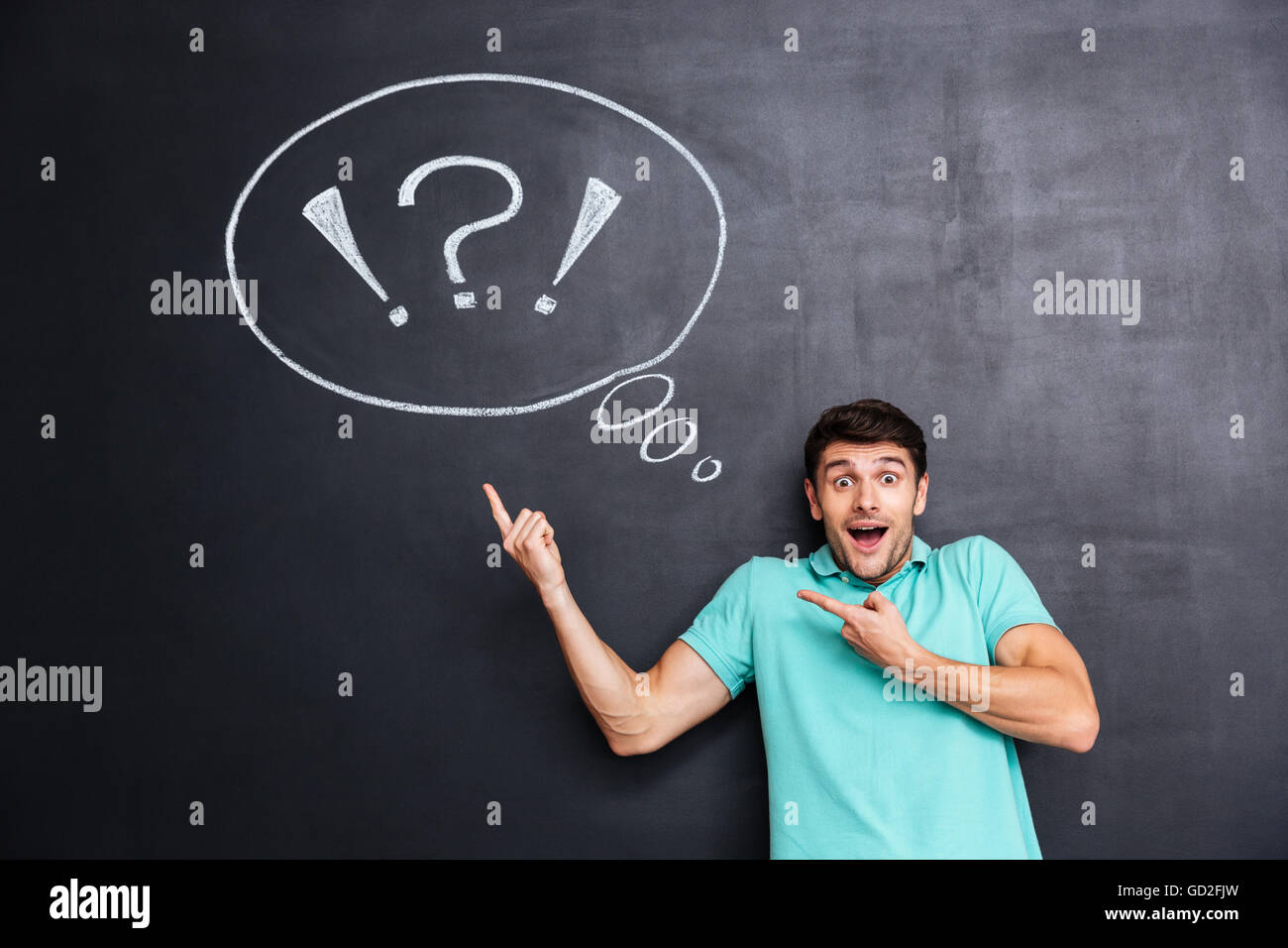 Wondered attractive young man pointing on thinking bubble over ...