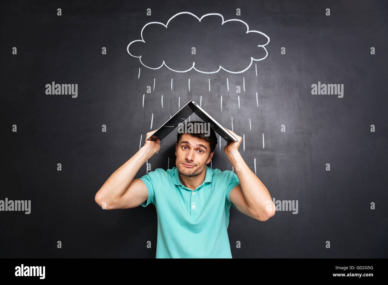 Upset tired young man imitating roof with latop and covering from drawn ...