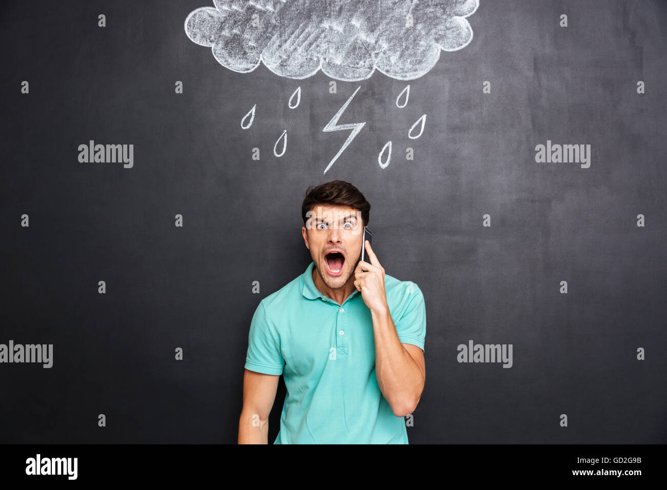 Angry aggressive man shouting and talking on cell phone standing with ...