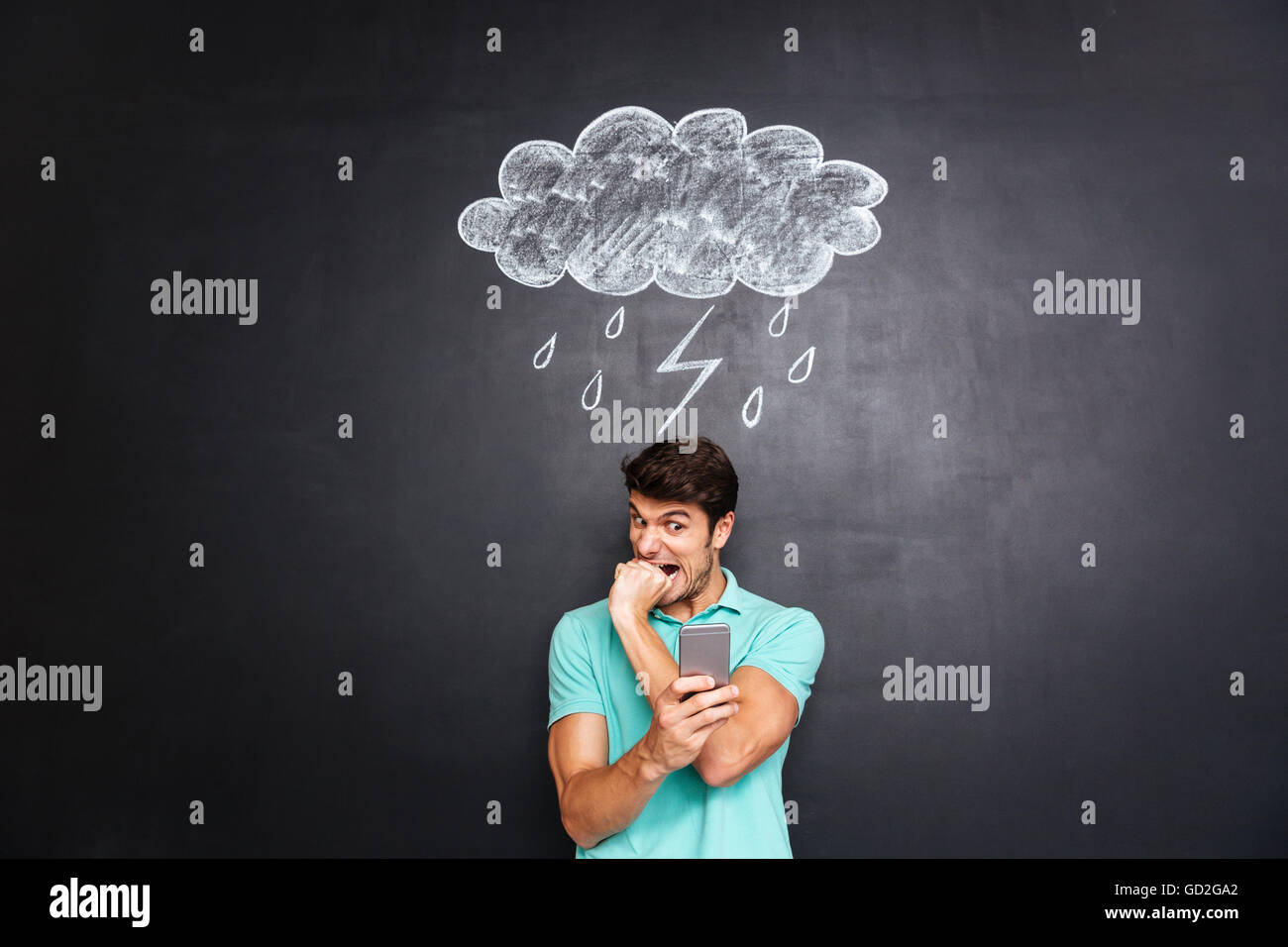 Frustrated nervous young man looking at mobile phone with black board ...