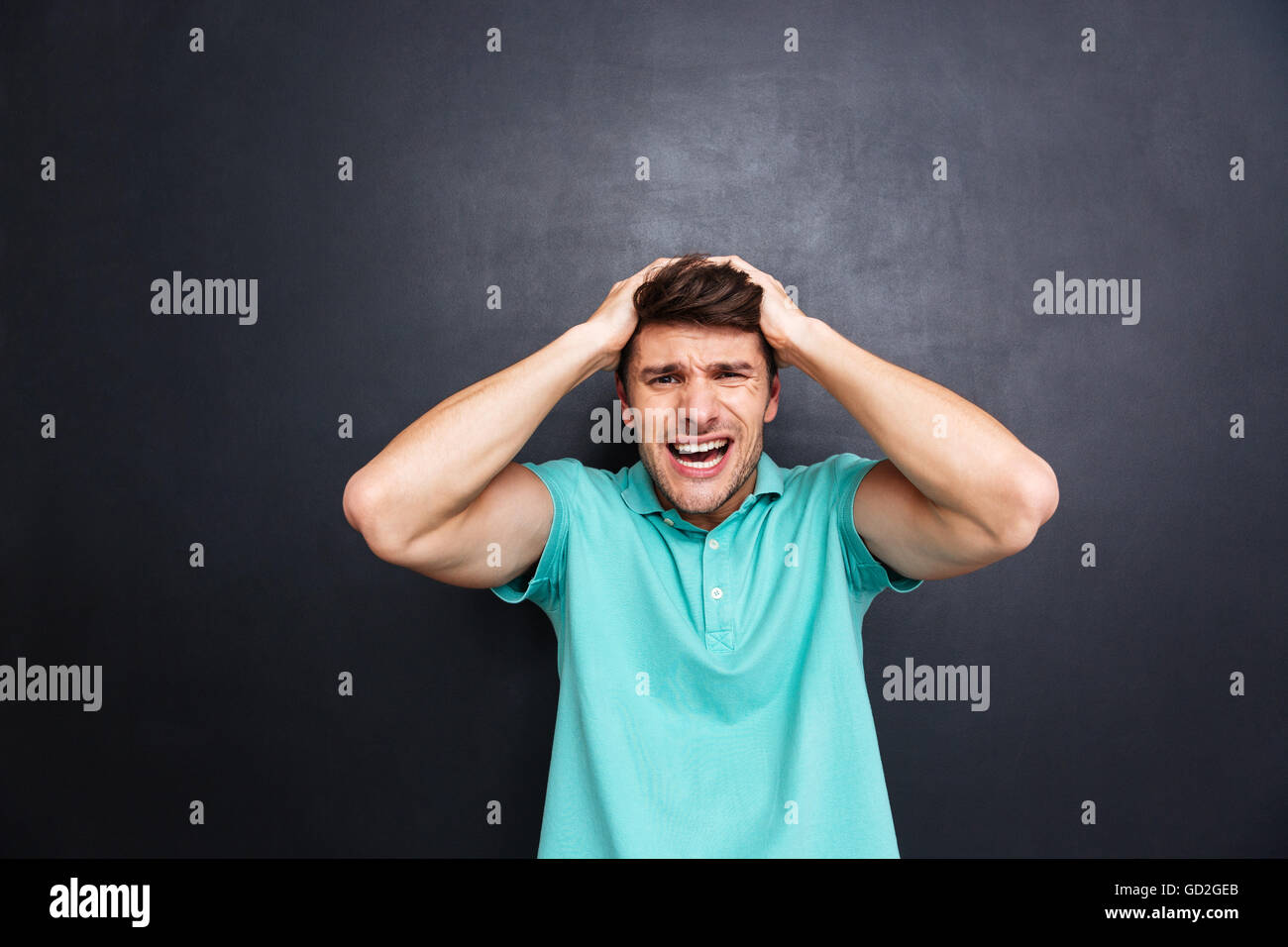 Portrait of a crazy young man shouting isolated over black chalkboard ...