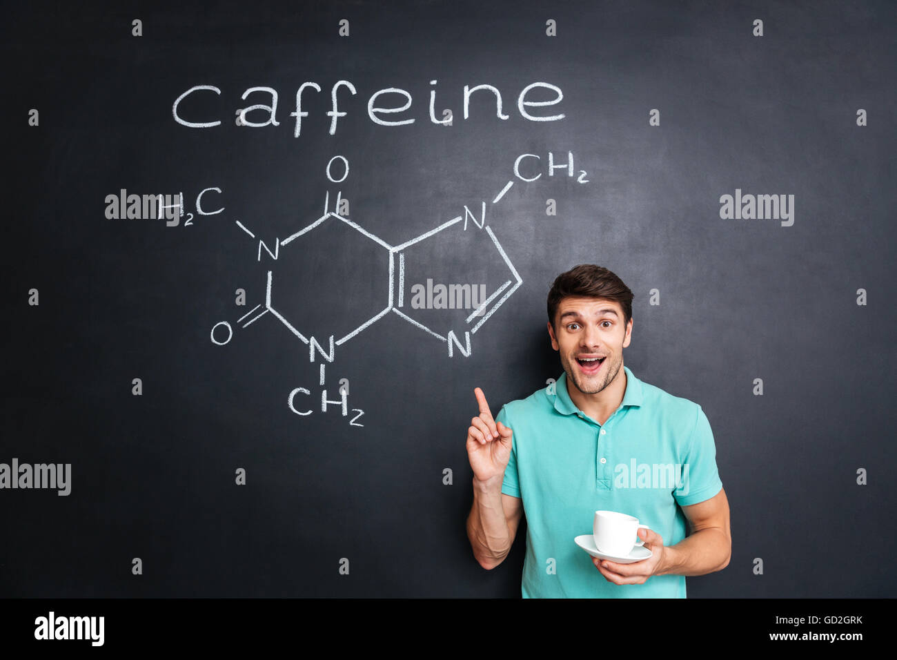 Smiling young man drinking coffee and pointing on drawn caffeine ...