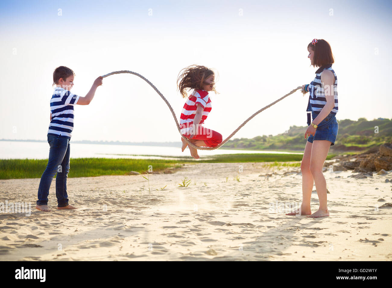 Summer family vacation - girl playing with skipping rope on the beach ...
