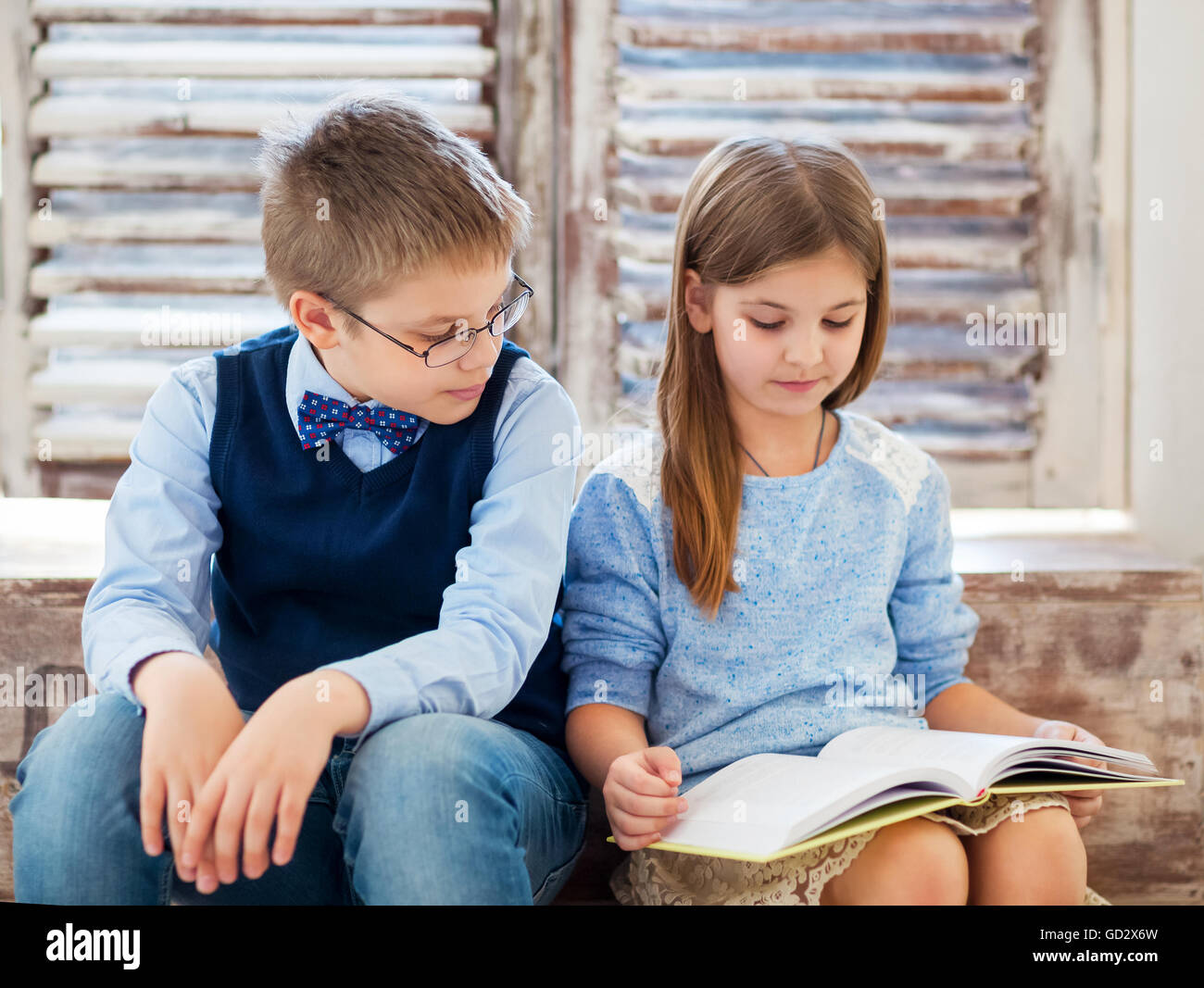 Brother and sister reading book in living room Stock Photo - Alamy
