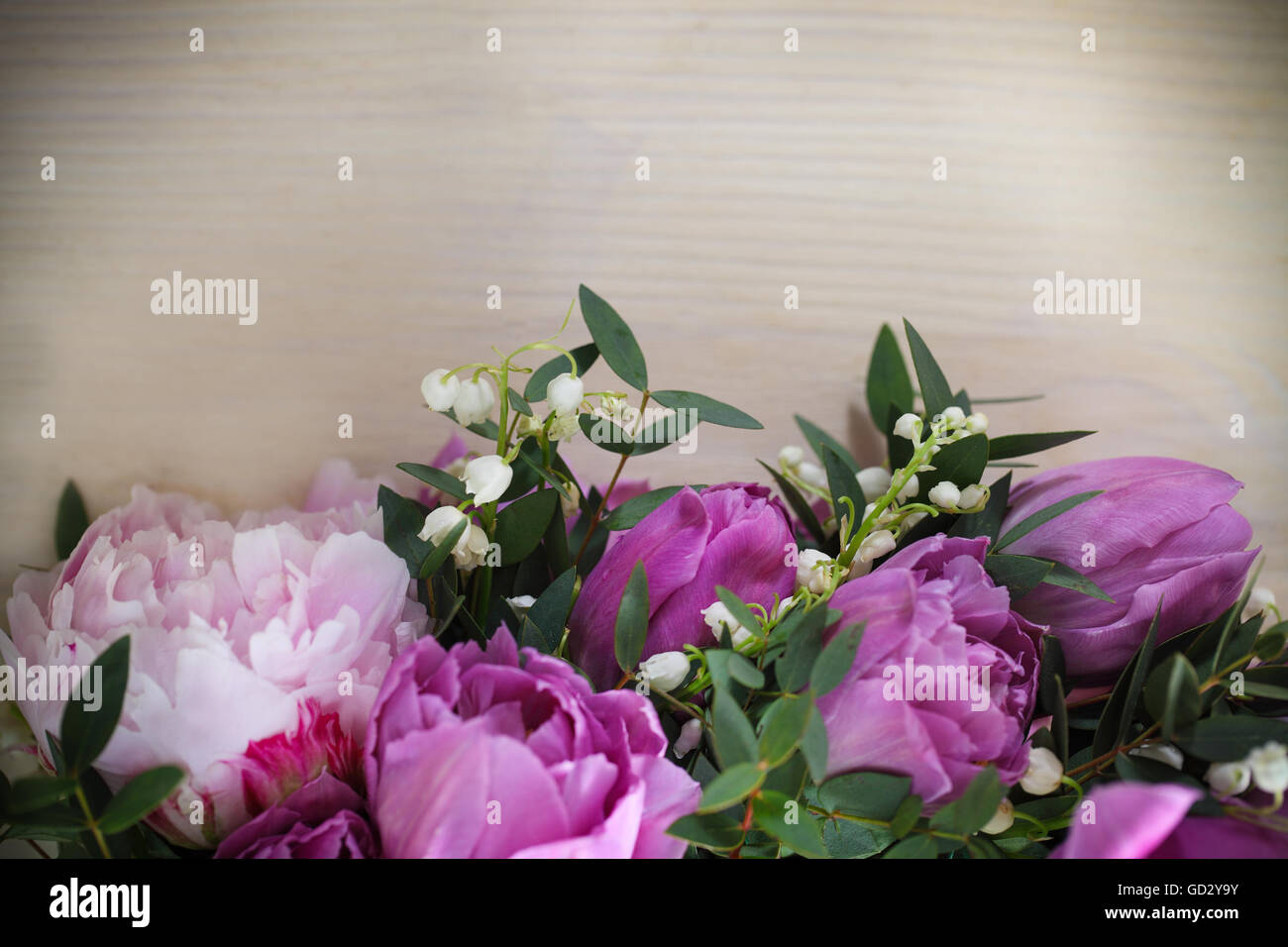 Pile of fresh pink tulips and lily of the valley on aged wooden table ...