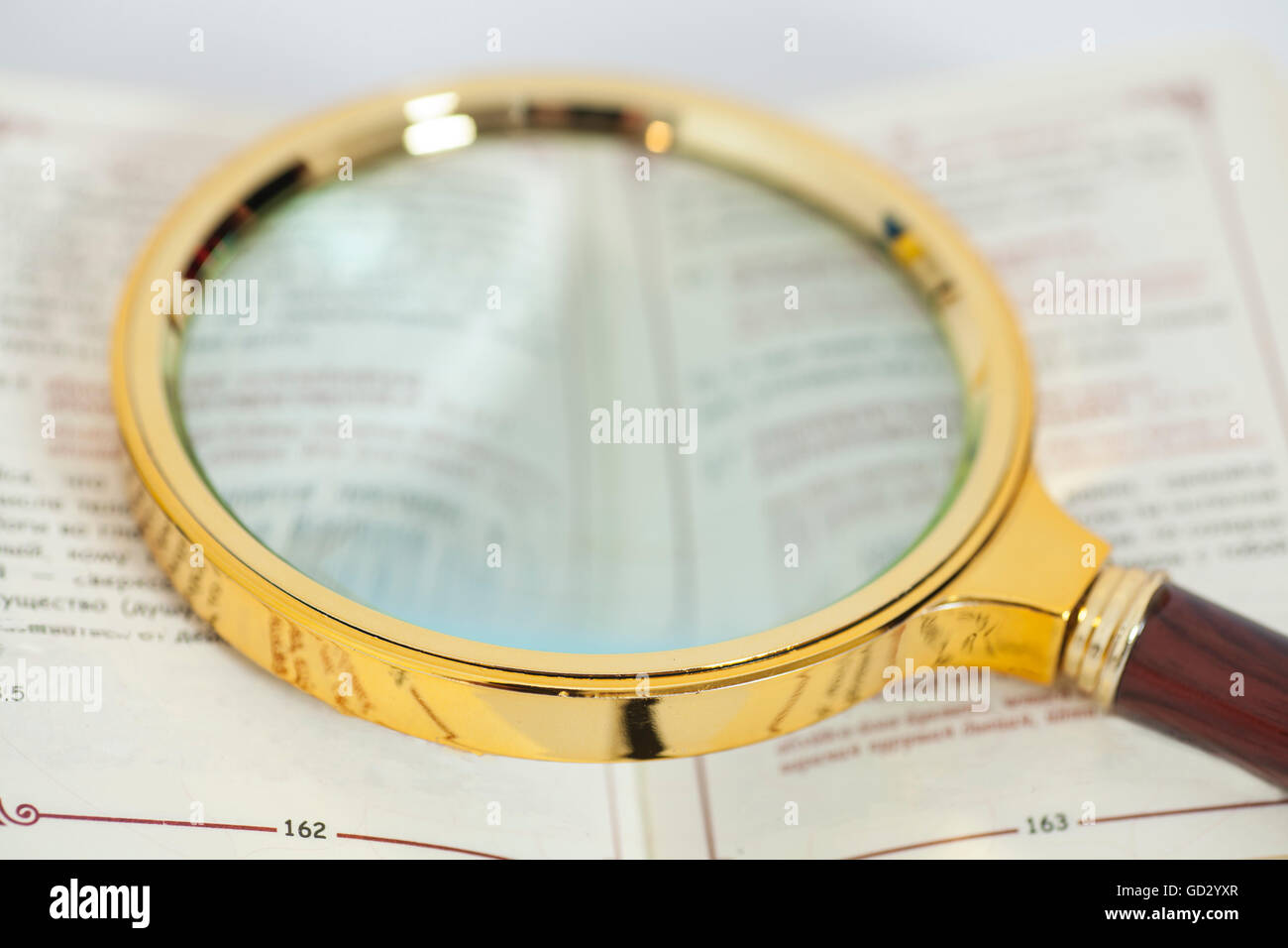 Open book with magnifying glass over white background Stock Photo - Alamy