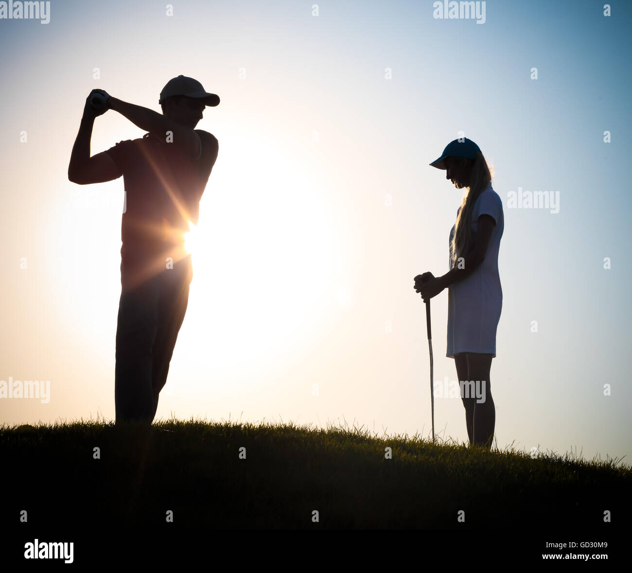 Male and female golfers playing golf at sunset Stock Photo - Alamy