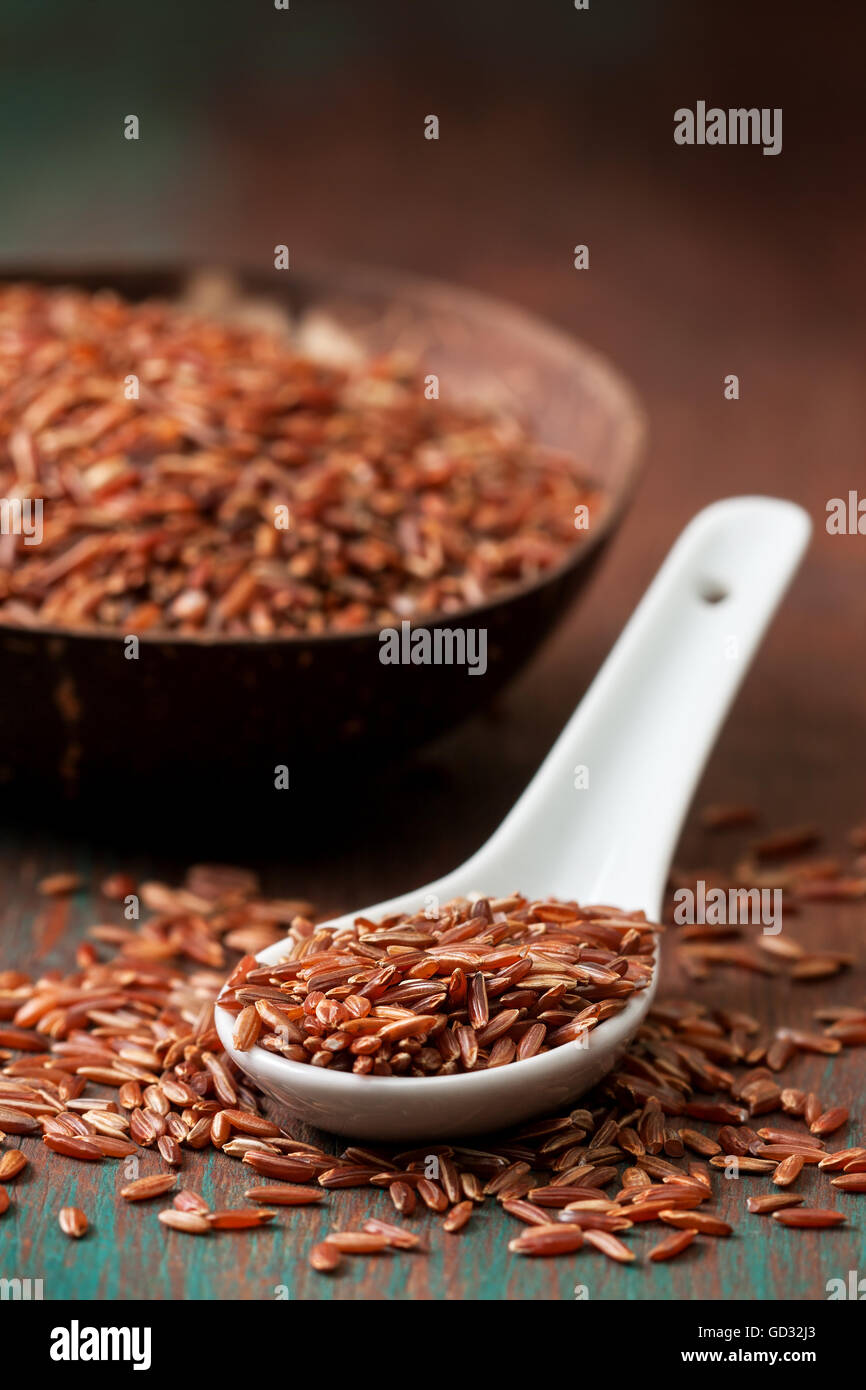 The spoon with red rice, bowl with rice on a wooden background ...