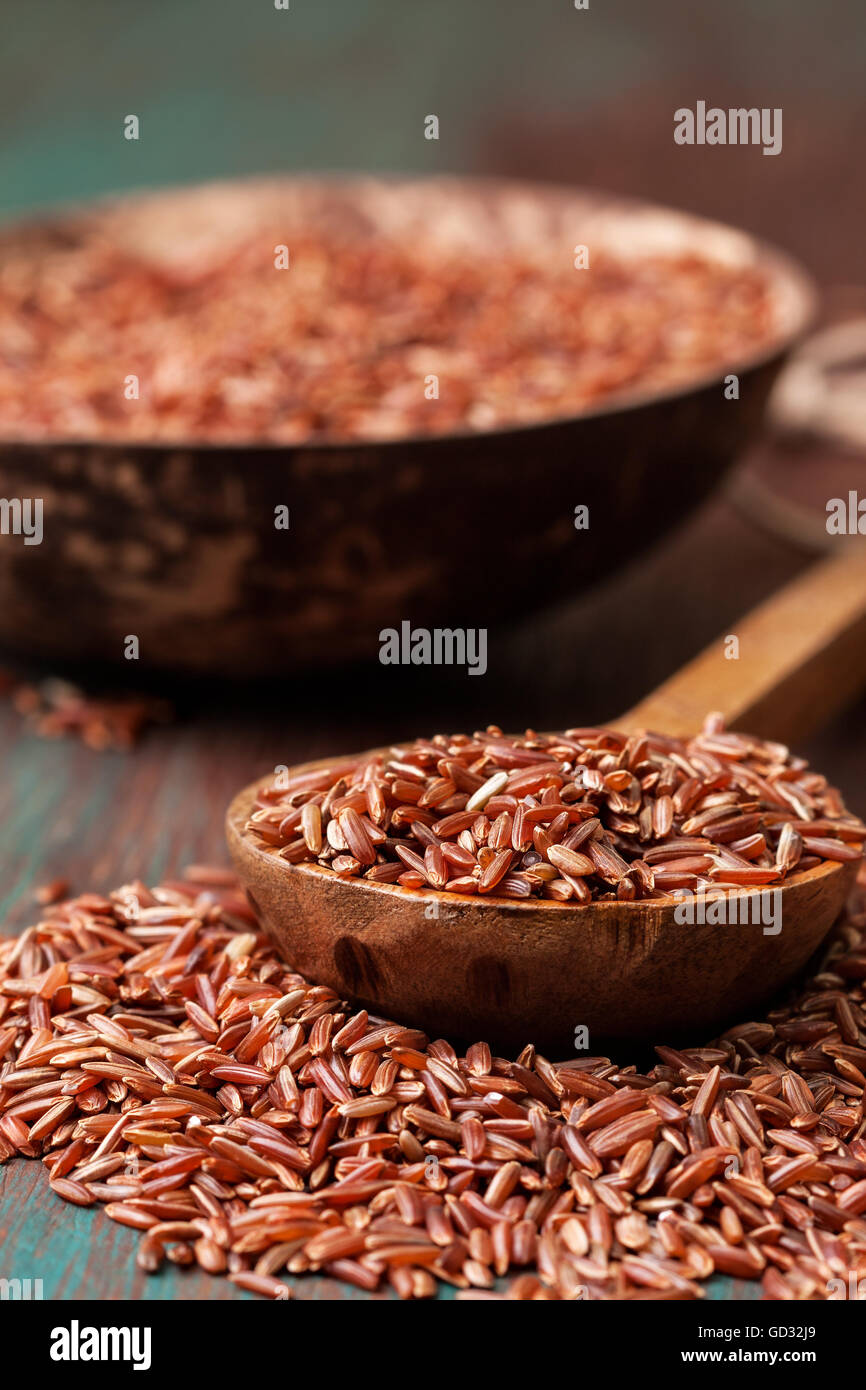 The spoon with red rice, bowl with rice on a wooden background ...