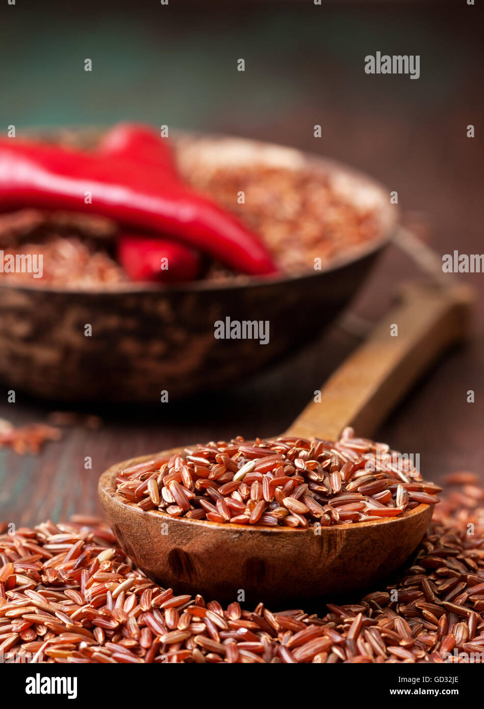 The spoon with red rice, chili peppers, bowl with rice on a wooden ...