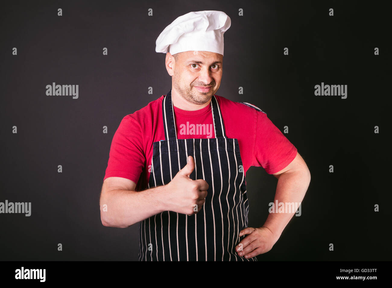 Portrait of a cook man doing a success symbol against a black ...