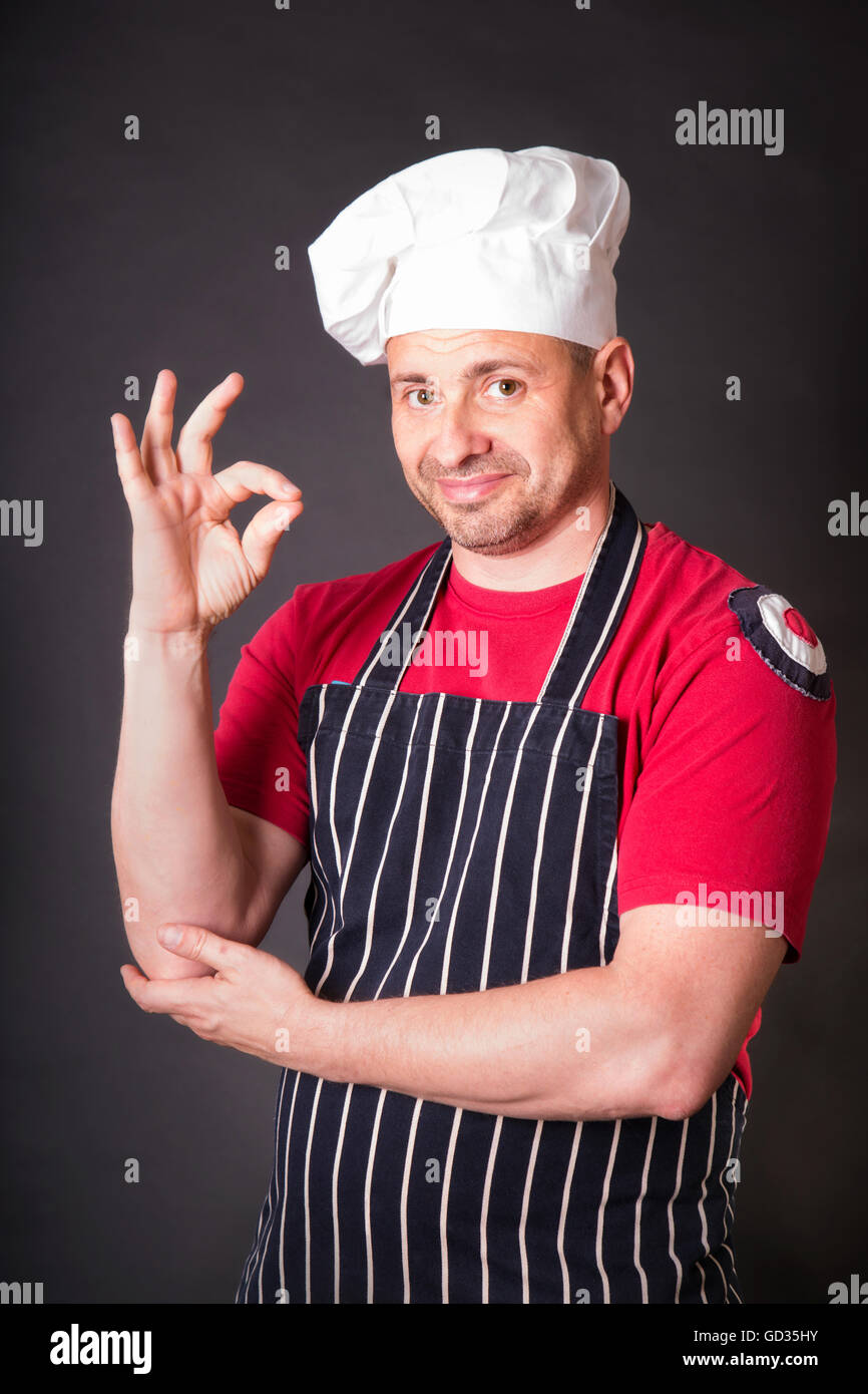 Portrait of cook with gesture okay in the studio on a black background ...