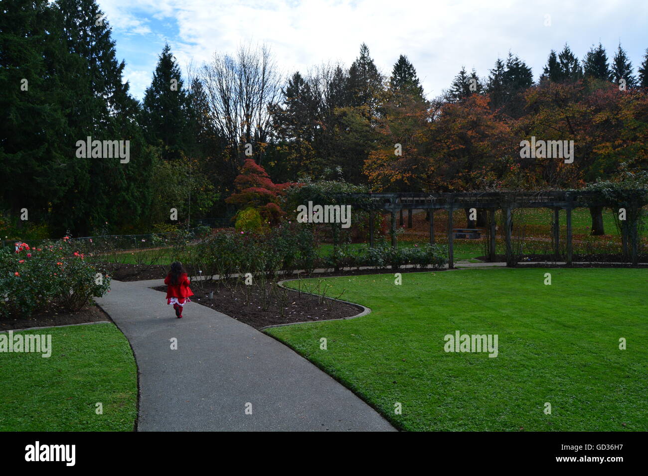 Little girl running through a garden in Autumn Stock Photo - Alamy