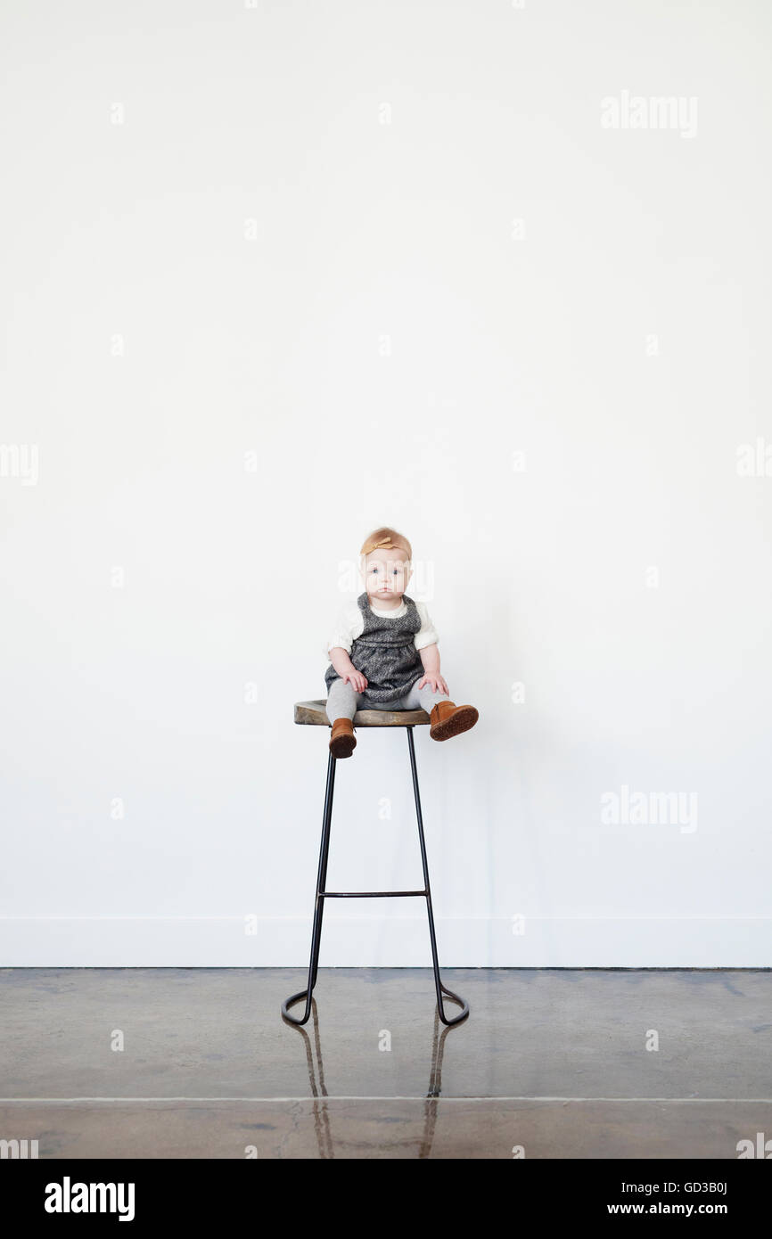 A young child, a little girl sitting on a tall stool laughing Stock ...