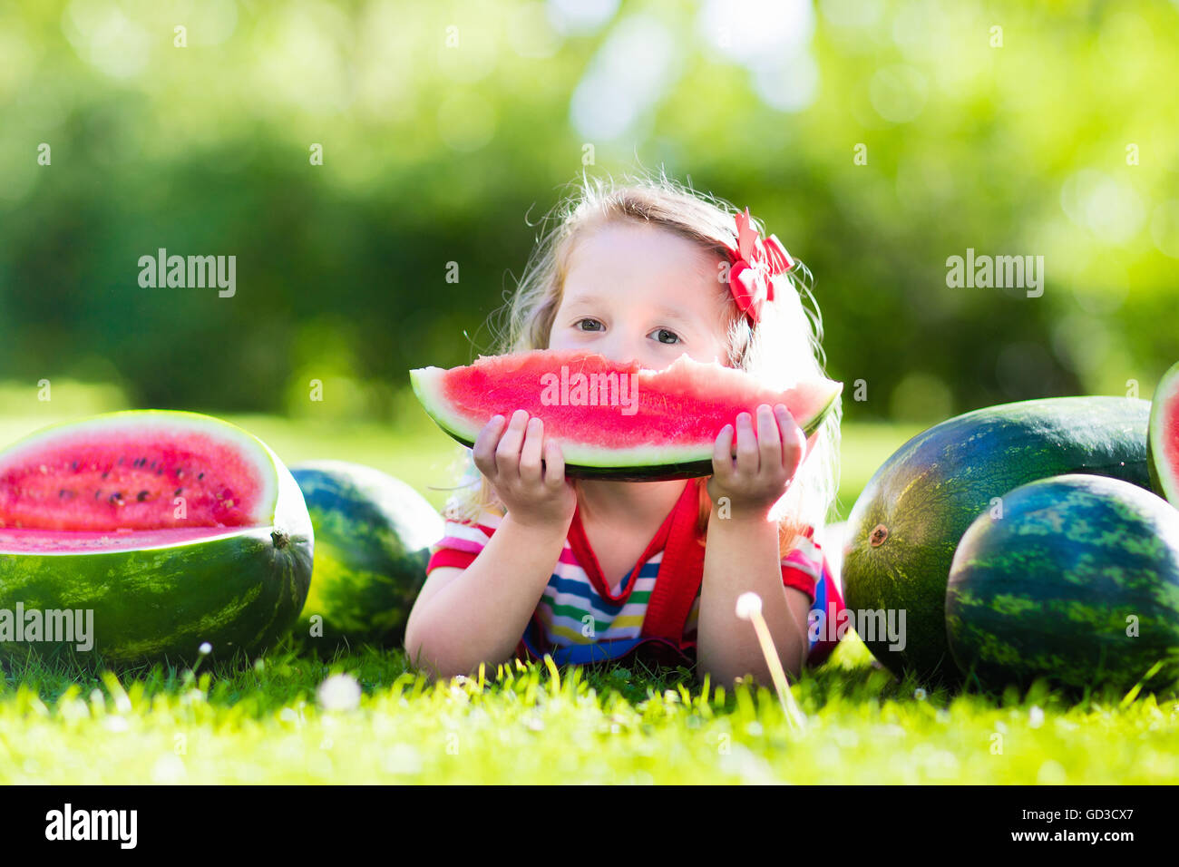 Child eating watermelon in the garden. Kids eat fruit outdoors. Healthy ...