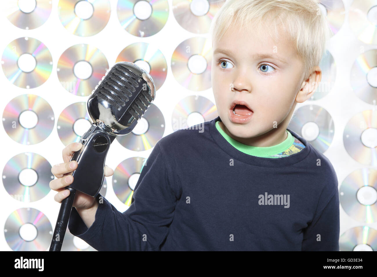 Small, pretty boy singing to microphone Stock Photo - Alamy