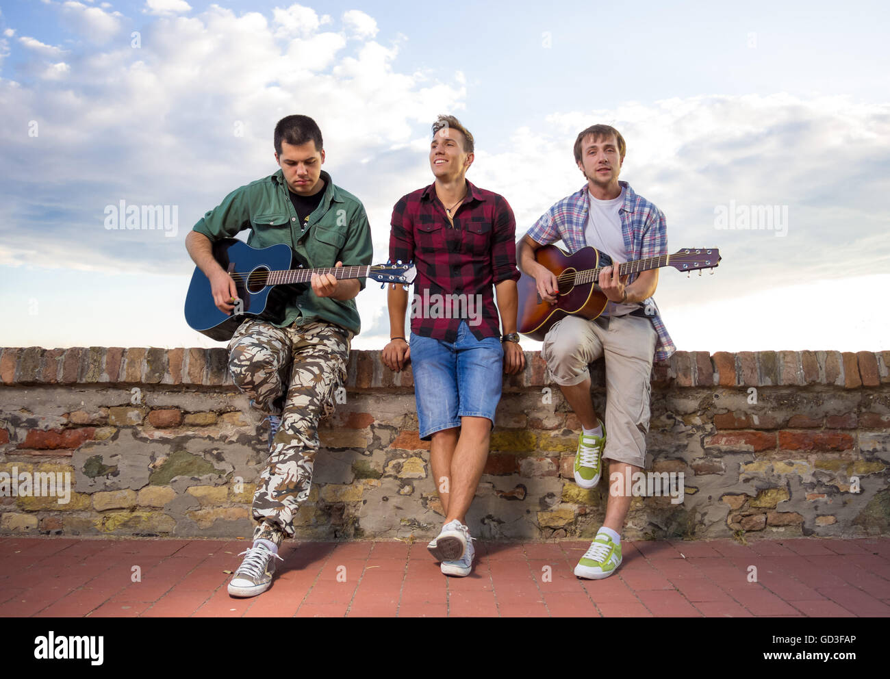 Three young men casual music band playing outdoors sunny Stock Photo ...