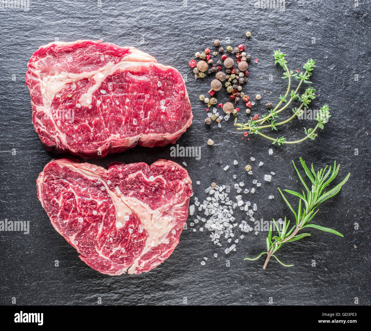 Rib eye steaks with spices on the black background Stock Photo - Alamy