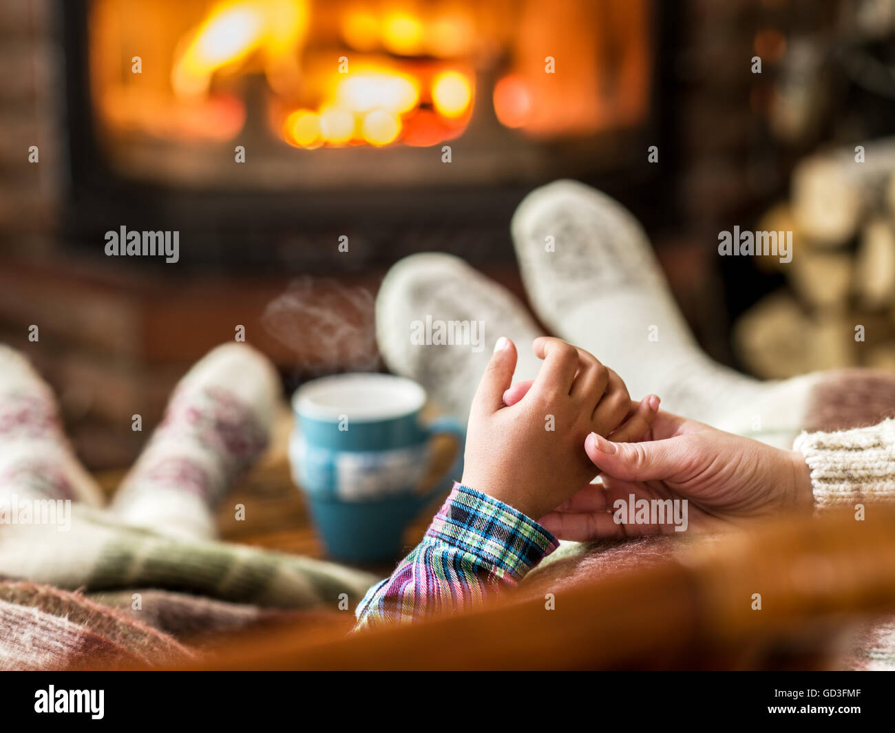 Warming and relaxing near fireplace. Mother and daughter holding hands ...