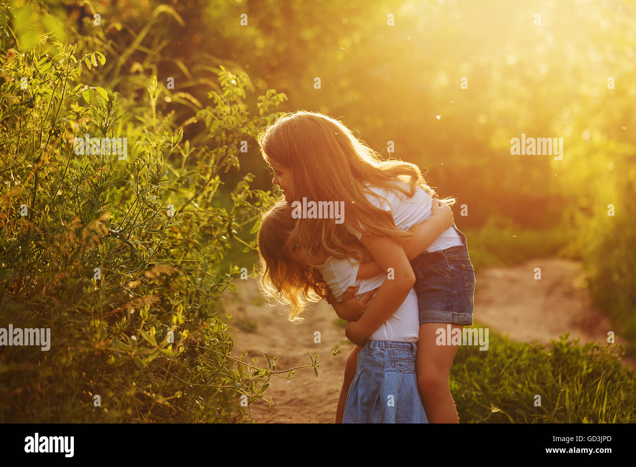 Two little sisters big hug in park on a sunny summer day. Family time ...