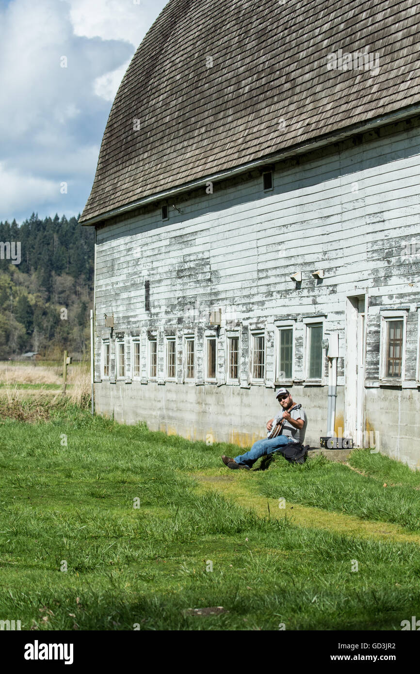 Man playing a banjo next to an old barn in Nisqually National Wildlife ...