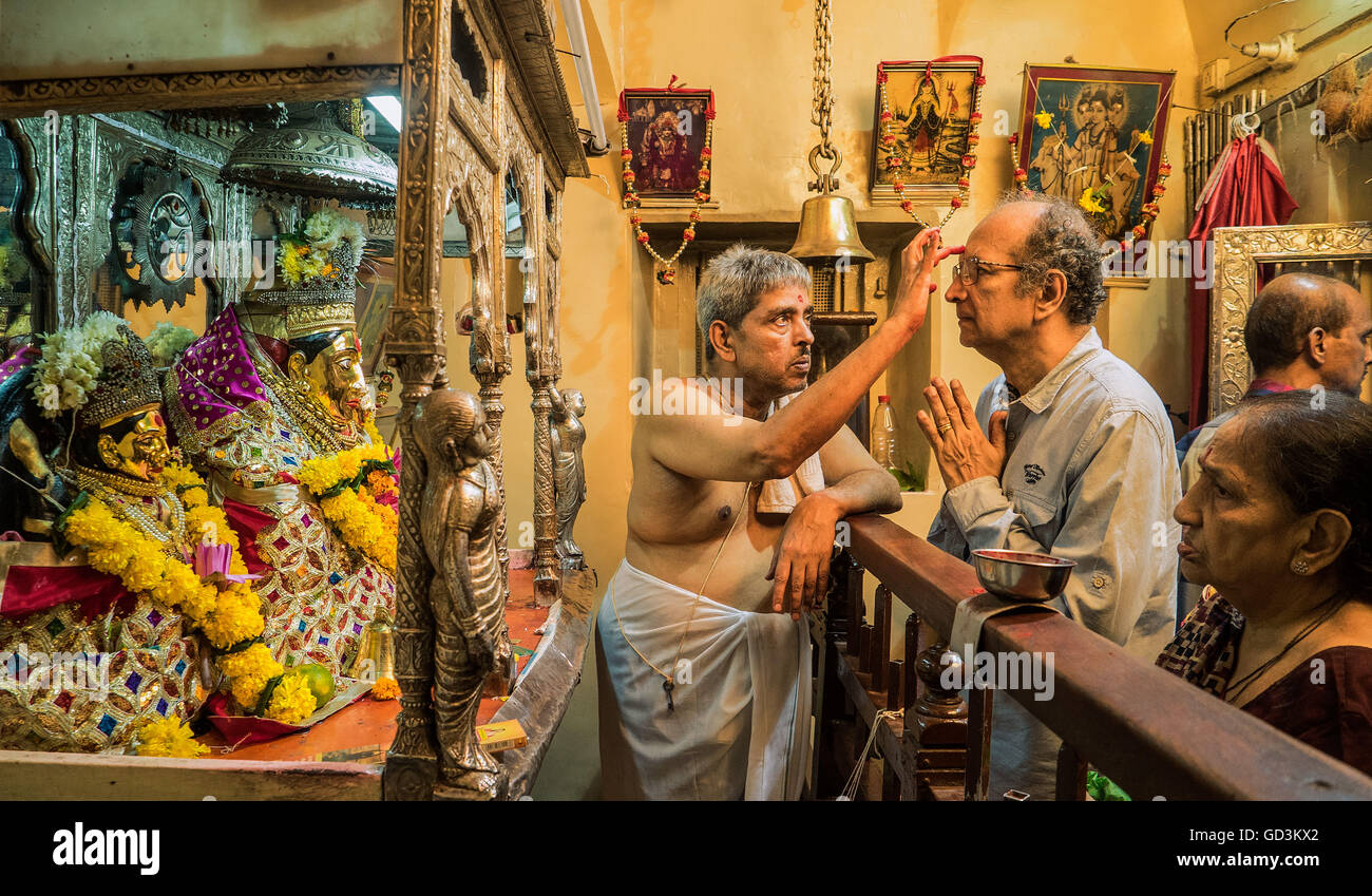 Devotee praying in Kalbadevi Temple, pandit priest applying tilak ...