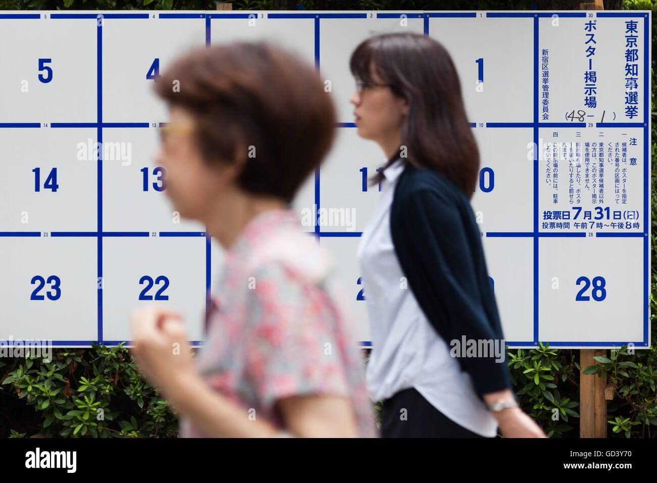 Pedestrians walk past an election poster board erected specifically for ...