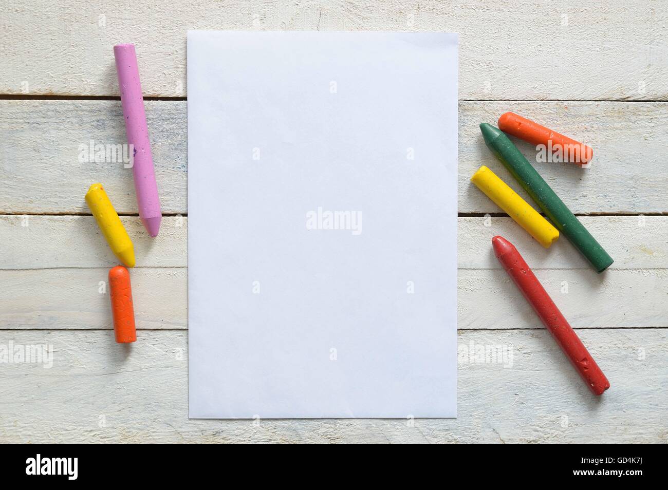 Paper and some crayons on a wooden table in a classroom. Empty copy ...