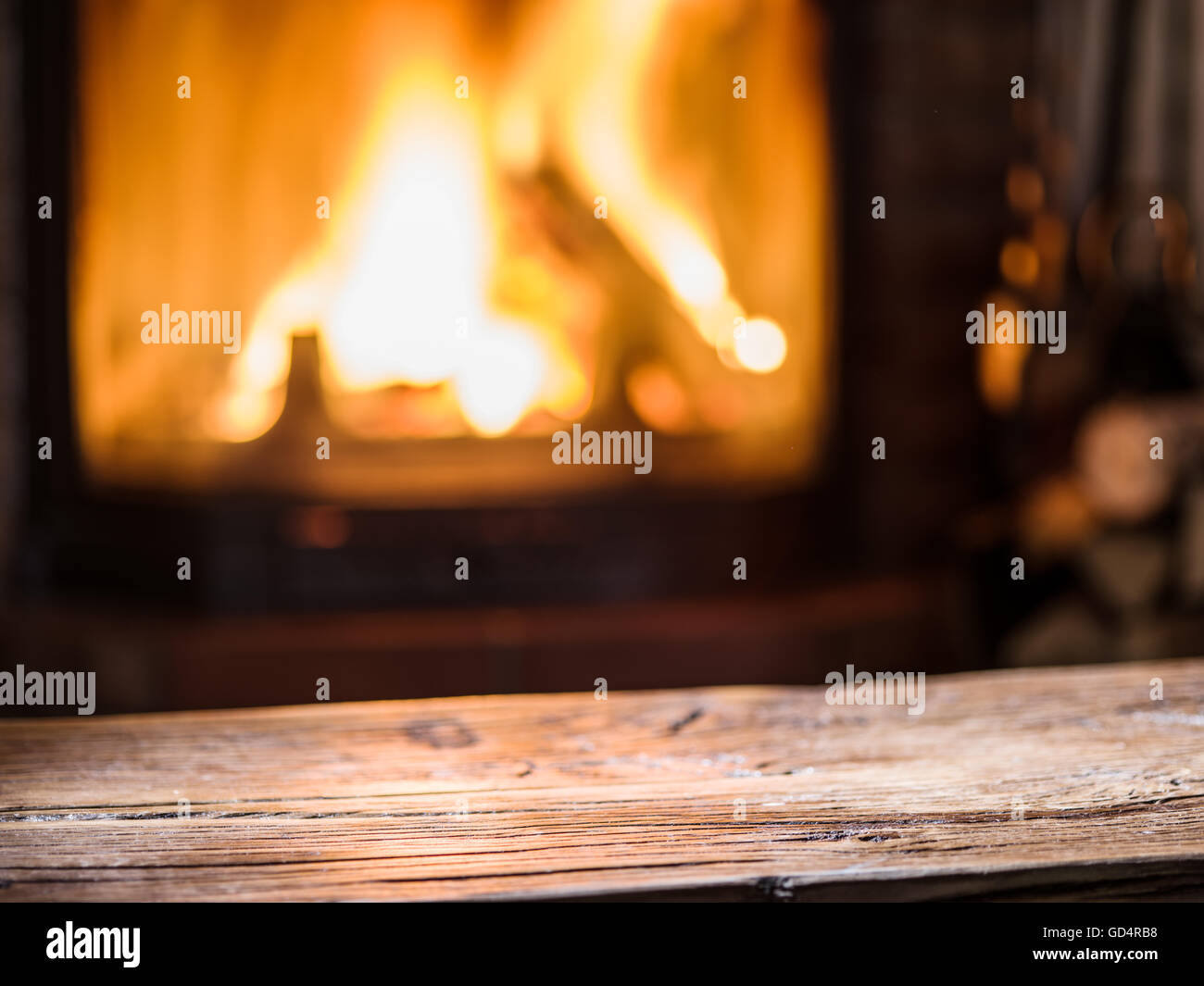 Old wooden table and fireplace with warm fire on the background Stock ...