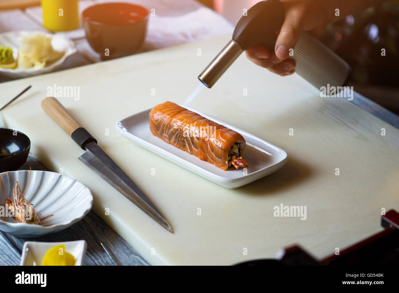Torch burner over sushi rolls. Man's hand holding torch burner. Chef ...