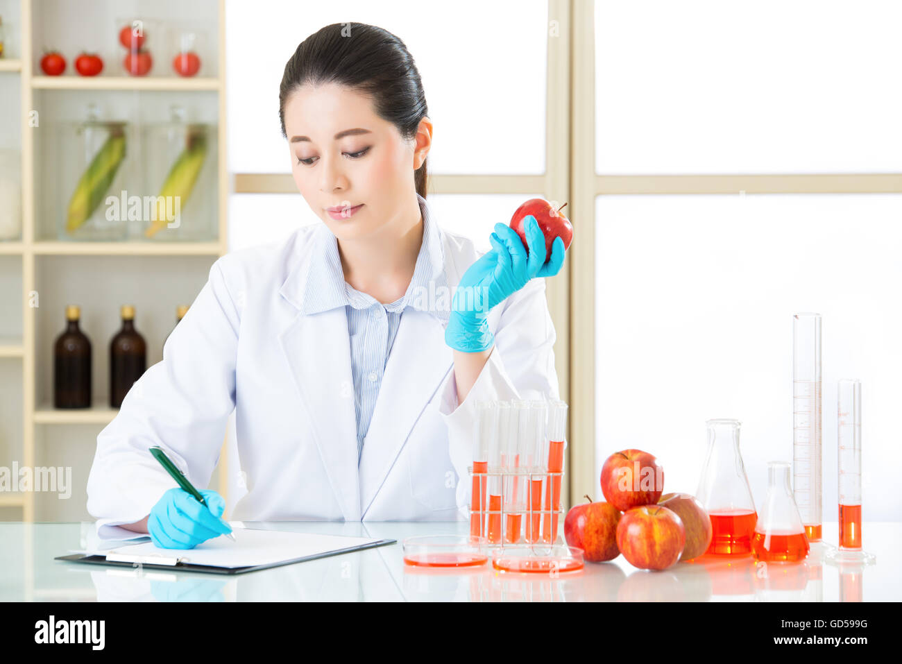 Asian female scientist holding an apple and recording the data on ...