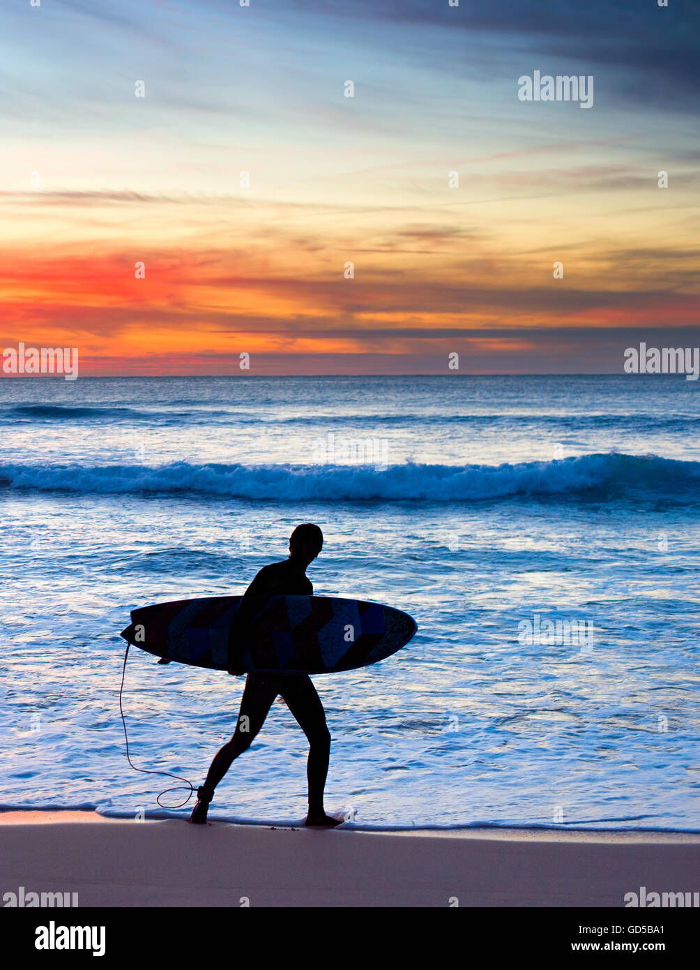 Surfer walking on the beach at sunset Stock Photo - Alamy