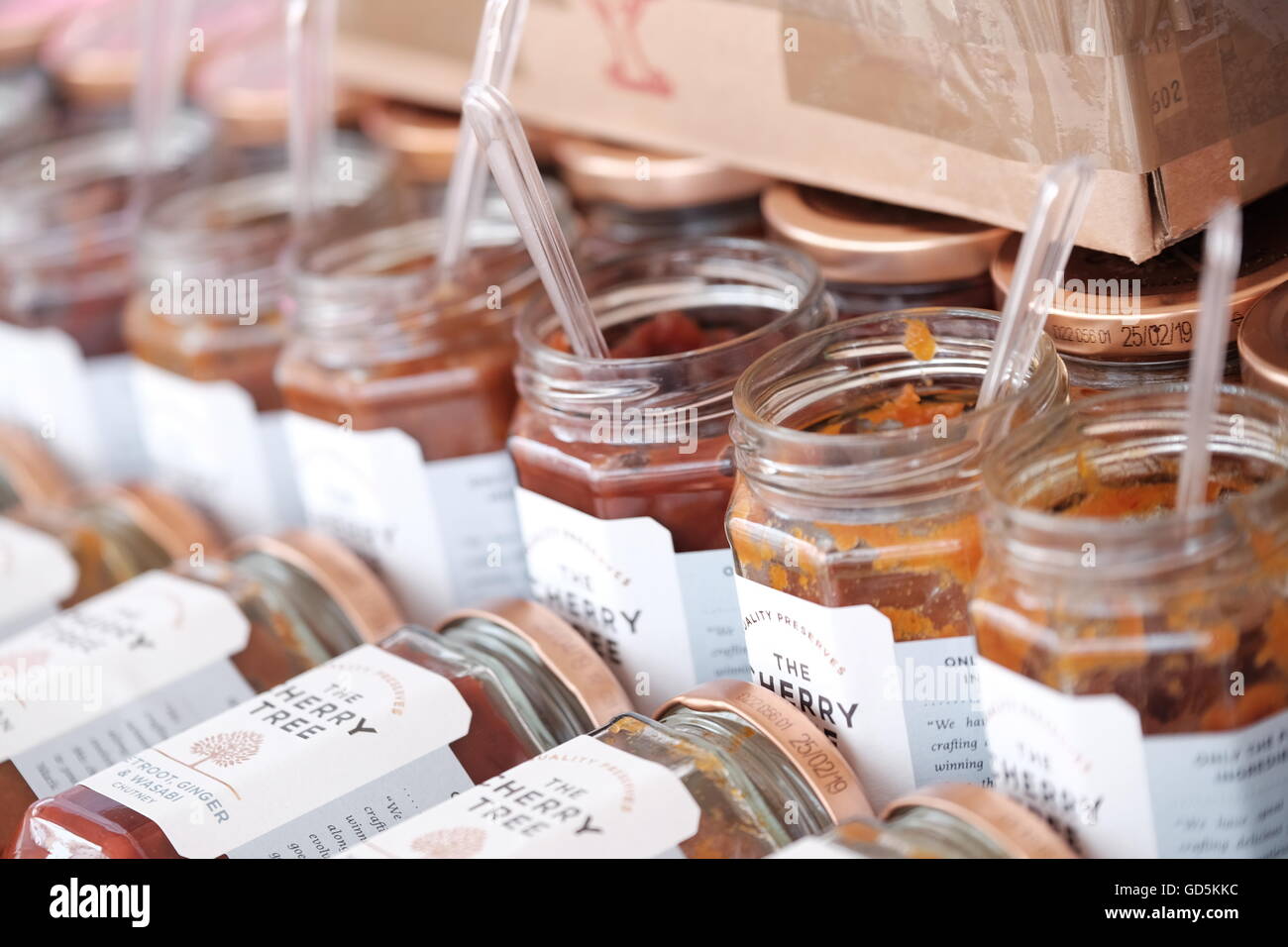 row of jars of preserves with spoons in Stock Photo - Alamy