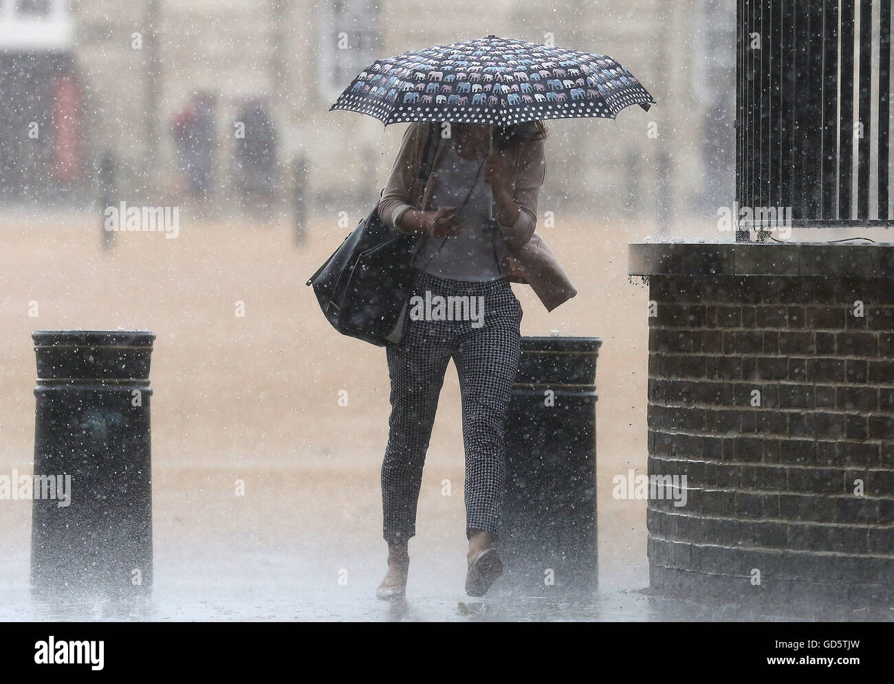 A woman walks through the rain off Horse Guards Parade in Westminster ...