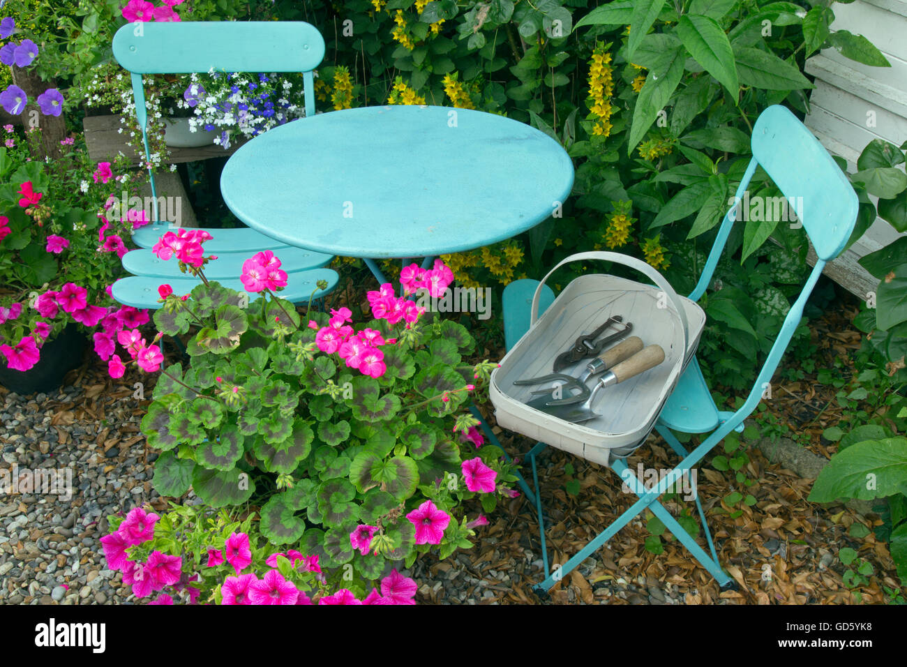 Pretty cottage garden with flower containers and blue table and chairs ...